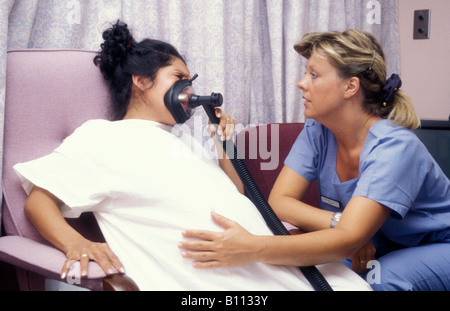 midwife supporting labouring hispanic woman in hospital with gas and ...