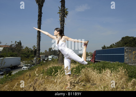 Woman performing yoga by busy freeway Stock Photo - Alamy