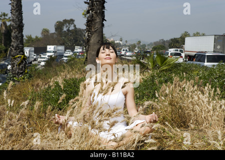 Woman performing yoga by busy freeway Stock Photo - Alamy
