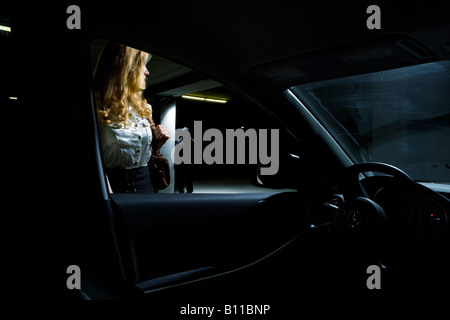 Woman approaches car and sees prowler in background Stock Photo - Alamy