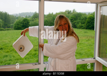 Woman throwing scales out of window overweight Stock Photo - Alamy