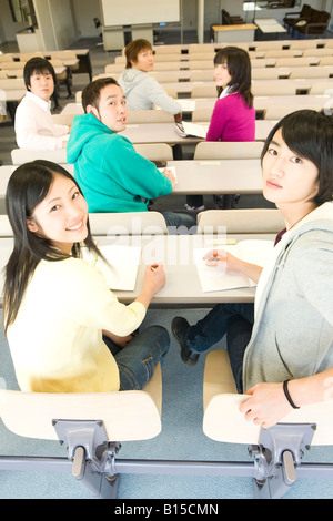 Asian female student with male classmates using smartphone standing in ...