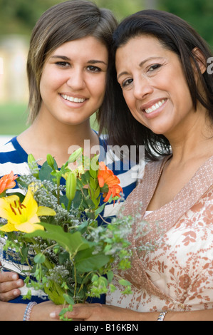 Hispanic mother and daughter holding bouquet of white flowers pointing ...