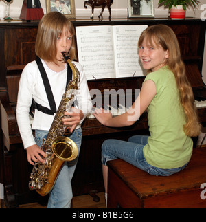 Little girls playing the saxophone and the piano Stock Photo - Alamy