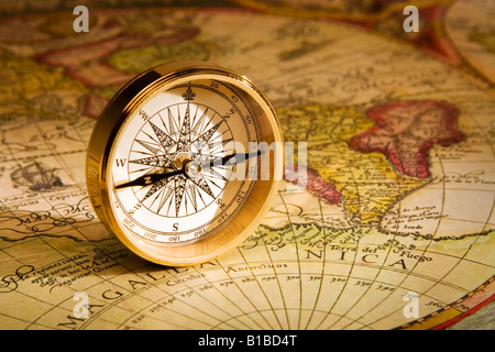 An antique gold compass set upon a sixteenth century map of the world ...