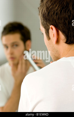 Reflection of man shaving with electric razor at bathroom Stock Photo ...