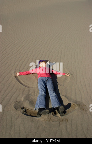 Girl making angel in sand on beach, high angle view Stock Photo - Alamy