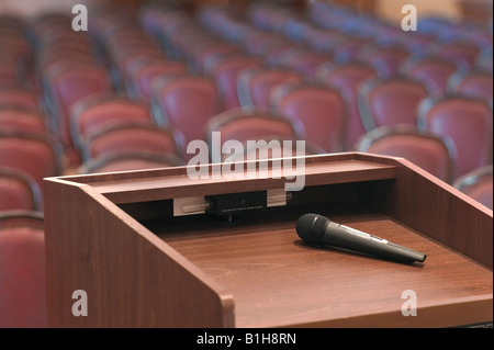 Closeup of microphone and podium with empty chairs in conference room ...
