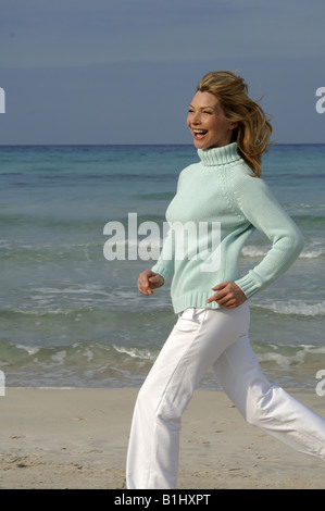 Running woman in turquoise pullover at the sea Stock Photo - Alamy