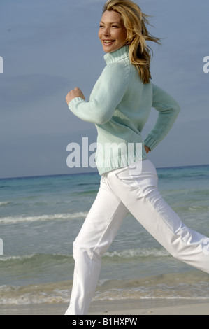 Running woman in turquoise pullover at the sea Stock Photo - Alamy