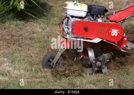 petrol driven garden rotavator being used to churn up soil in a garden ...
