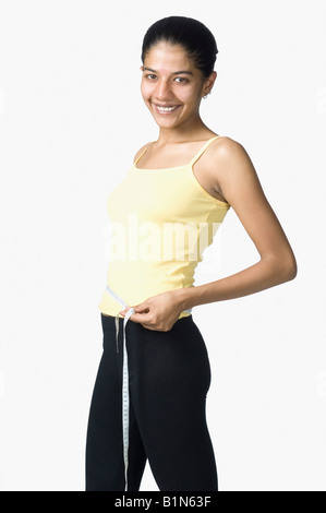 Side view of fitness woman with tape measure showing her waist on a ...