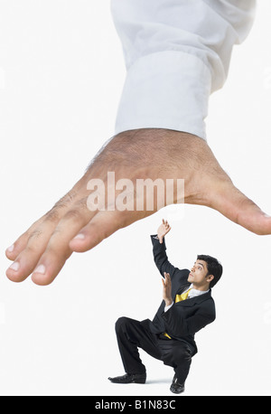 Businessman being crushed under a human hand Stock Photo - Alamy