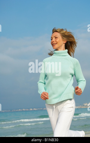 Running woman in turquoise pullover at the sea Stock Photo - Alamy