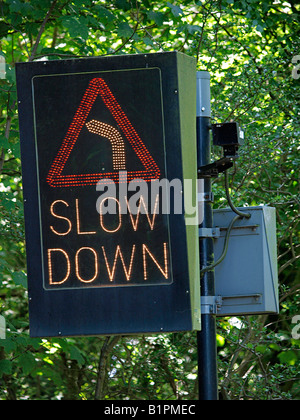 Electronic "slow down" road sign indicating a bend in the road to the ...
