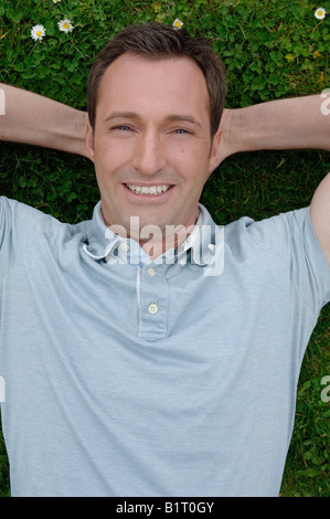 31-year-old man lying on the grass, smiling Stock Photo - Alamy