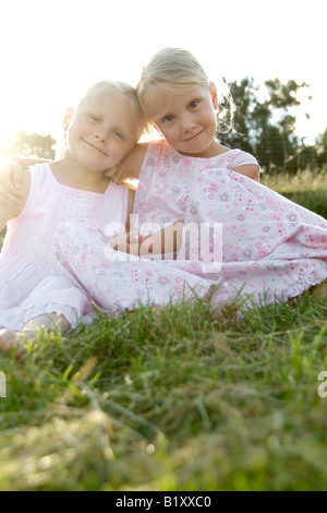 Portrait of two girl friends putting their arms around their shoulders ...