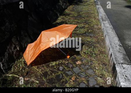 old orange umbrella left on pavement in town Stock Photo - Alamy
