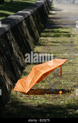 old orange umbrella left on pavement in town Stock Photo - Alamy