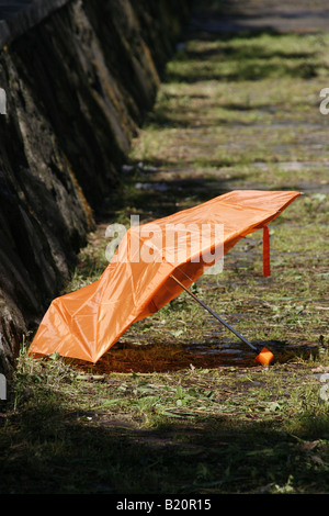 old orange umbrella left on pavement in town Stock Photo - Alamy