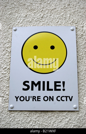 british cctv warning sign with yellow smiley face on white textured ...