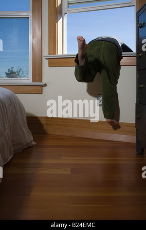 Boy climbing out of window Stock Photo - Alamy