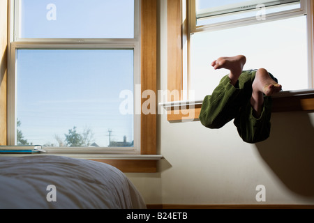 Boy climbing out of window Stock Photo - Alamy