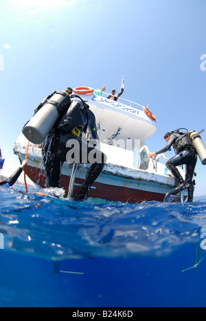 diver climbing up to a boat after finishing a dive in the Maldives ...