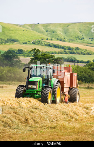 Agricultural scene. Tractor collecting hay bales in field and loading ...