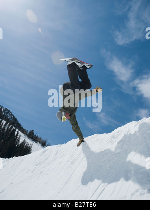 A young man performing a snowboard trick on a rocky surface by the ...