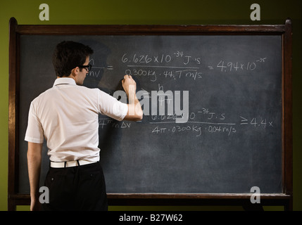 Solving the equation. a young man writing on a whiteboard in a ...