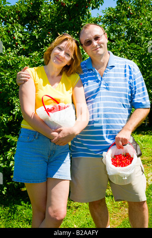 Happy mature couple picking fresh blueberries during shopping together ...
