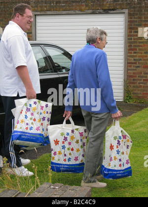 man helping elderly woman carry in bag for life reusable ...