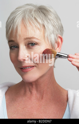 Mature woman using blush brush Stock Photo - Alamy