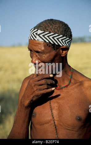 A portrait of a Bushman wearing a beaded headband and neck adornment ...