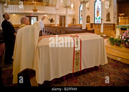 A priest waves a sensor over the casket at a Catholic funeral mass in ...