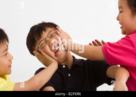 Two children pushing a boy's mouth Stock Photo - Alamy
