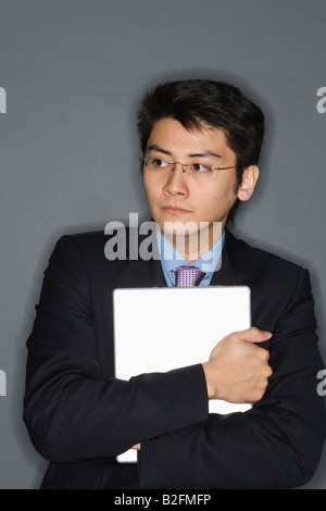 Businessman hugging laptop at studio Stock Photo - Alamy