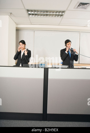 Two businesswomen talking over cubicle wall Stock Photo - Alamy