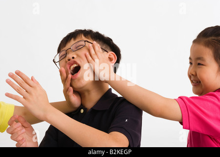 Two children pushing a boy's mouth Stock Photo - Alamy