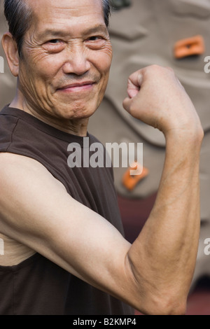 Senior man smiling and flexing muscles confidently in a rehabilitation ...