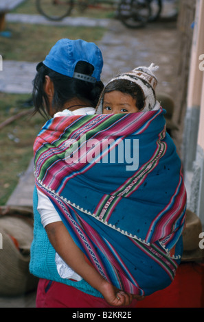 Indian woman carrying child with Inca stone wall, Sacred Valley, Cuzco ...