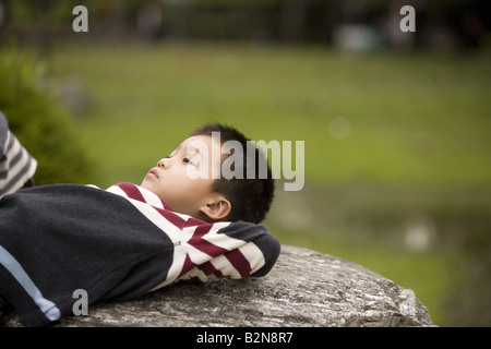 Side profile of a boy lying on a rock Stock Photo - Alamy