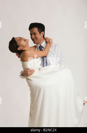 A vertical shot of the couple- the groom carrying the bride in his arms ...