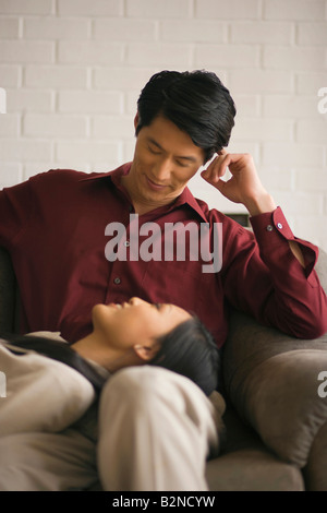 Asian man resting on couch using smartphone while sick at home Stock ...