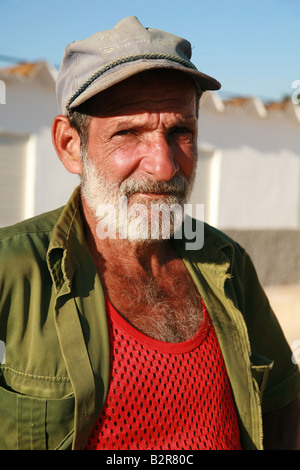 A 60-70 year old Cuban Hispanic male sits on a crude wooden bench on ...