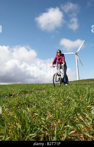 Wind farm with woman riding bike in foreground. Wind energy. Wind power ...