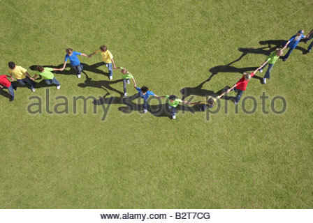 children in a line holding hands running in the playground of school ...