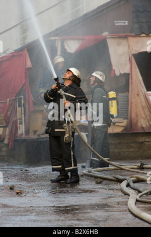 Firefighter man, water and spraying hose for emergency, rescue or ...