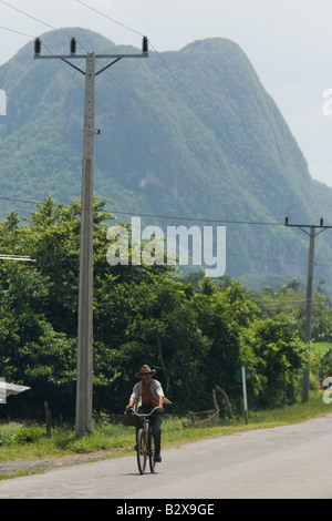 A large mountain formation called mogote overlooks a road near Vinales ...